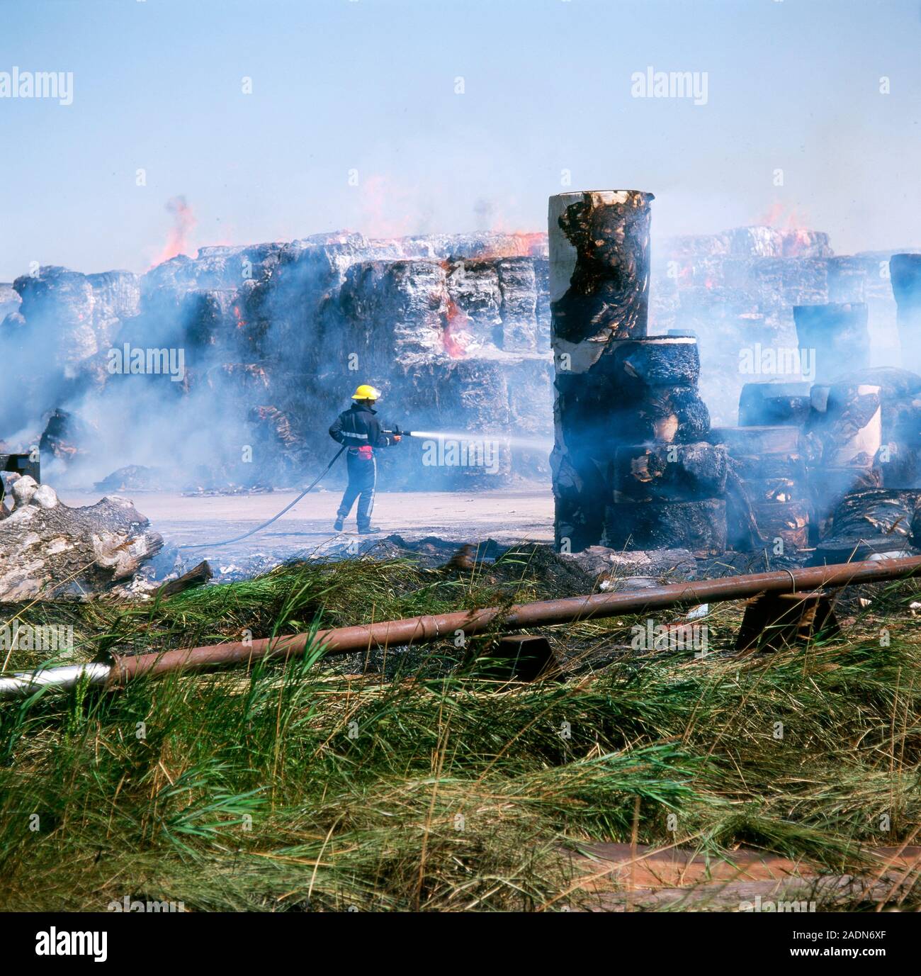 Industrial paper fire. Fireman using a hosepipe to extinguish a fire at ...