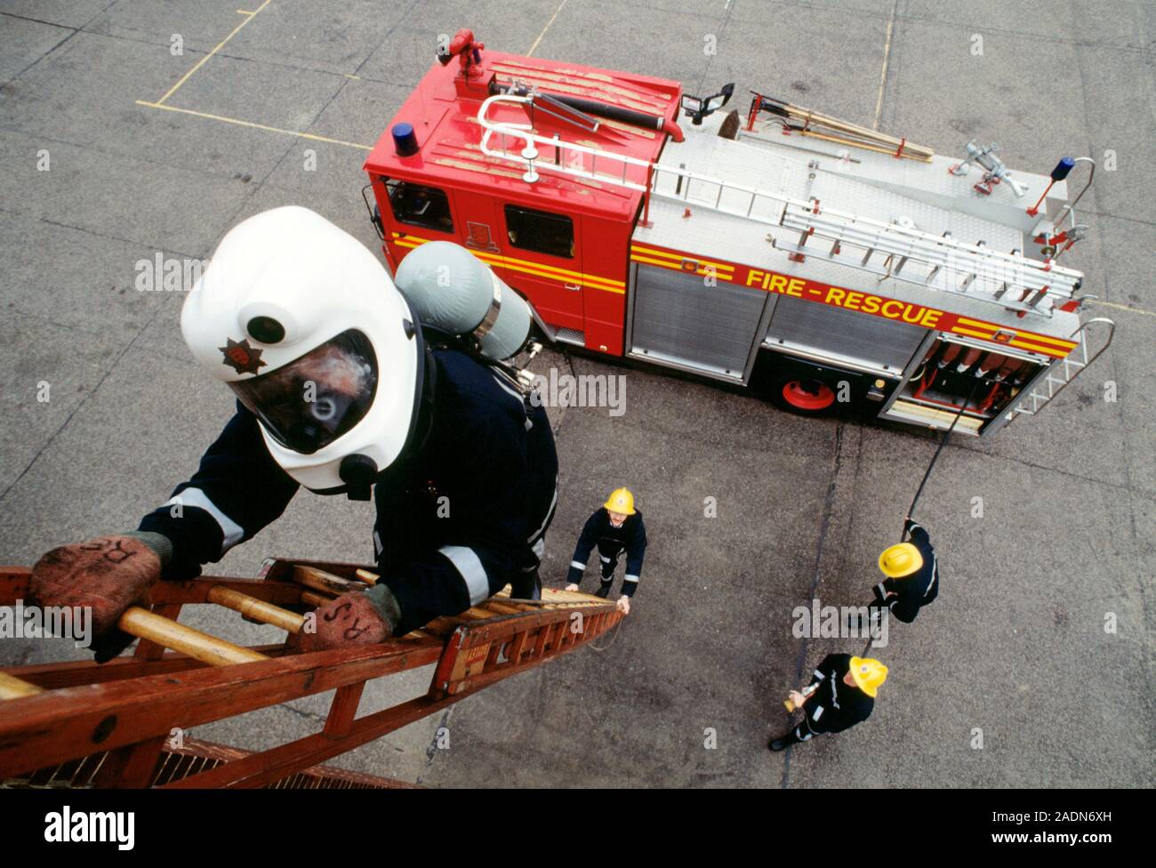Firefighter climbing a ladder. He is wearing protective clothing ...