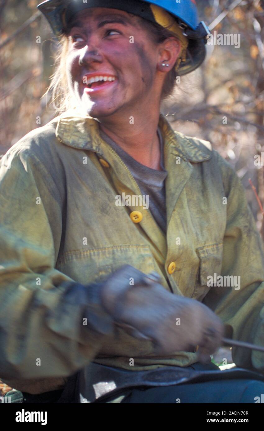 Female firefighter, sharpening her pulaski axe. This firefighter is ...