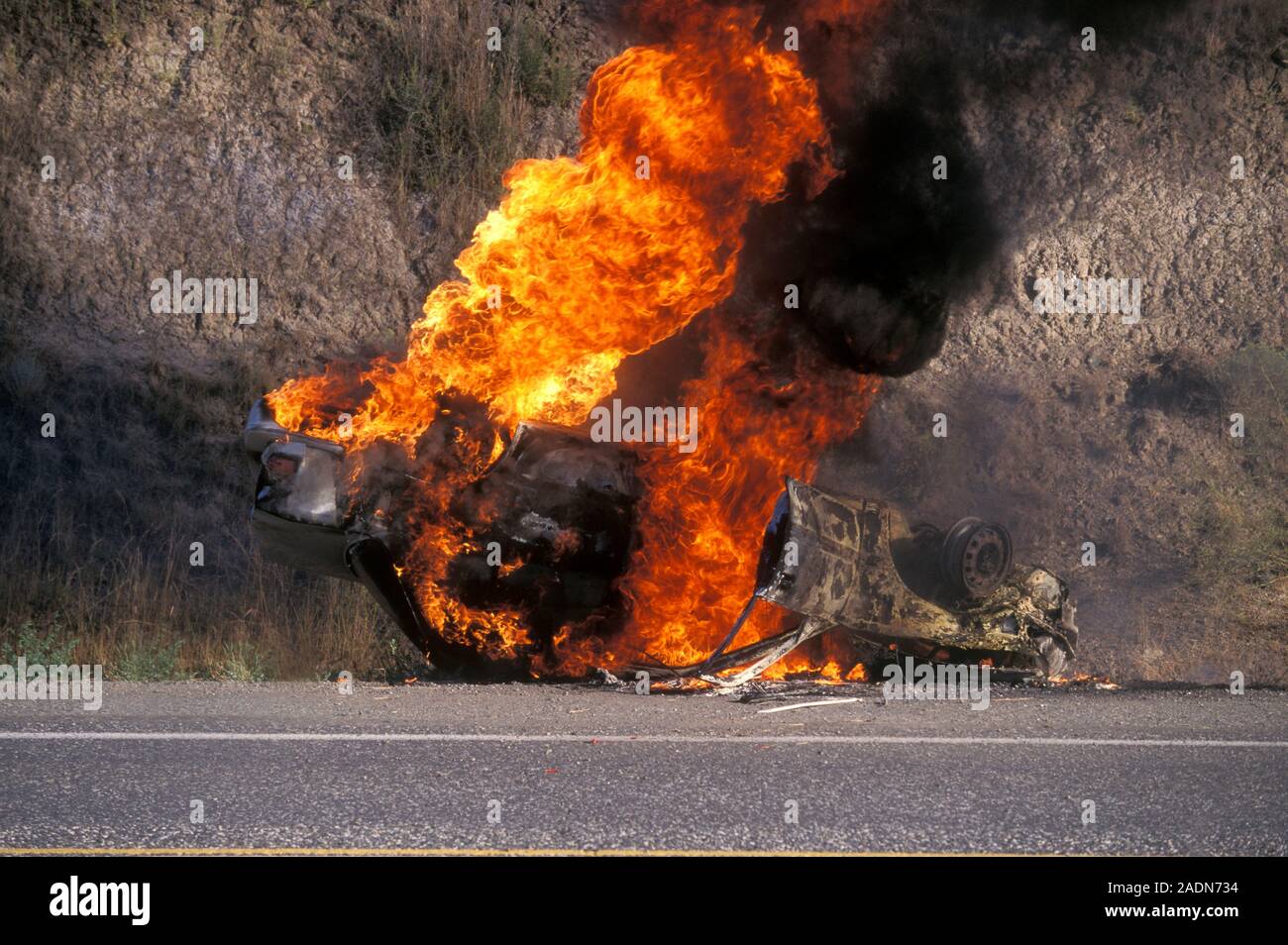 Car in flames. Car engulfed in flames after a road accident has caused ...