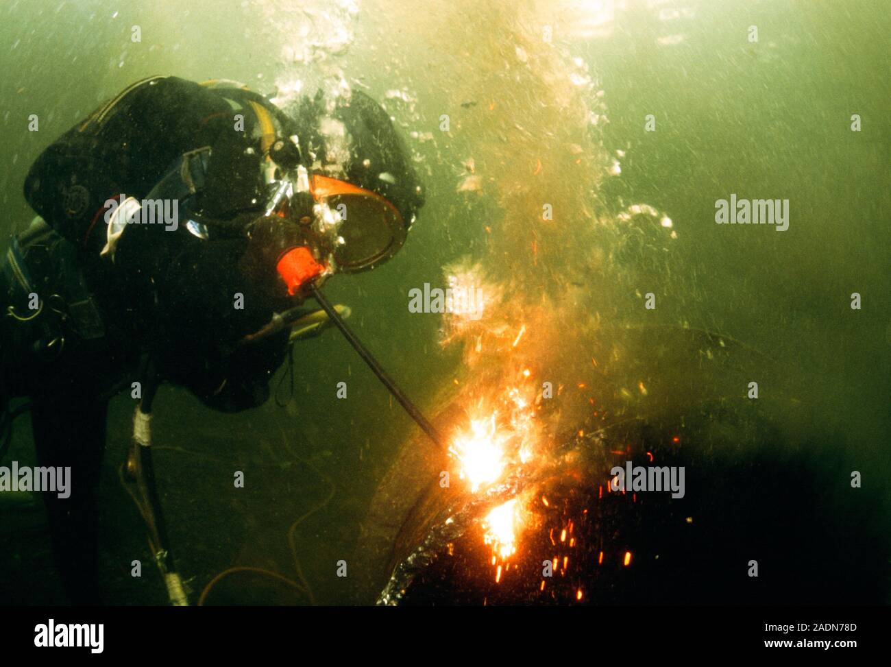 Welding underwater. Commercial scuba diver welding a metal pipe ...