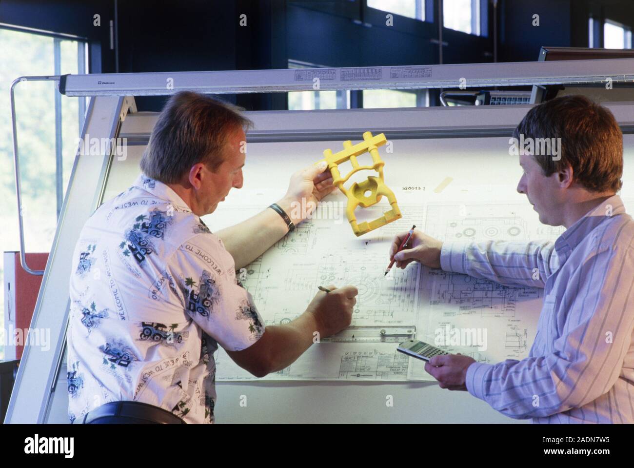 MODEL RELEASED. Machine design. Two engineers designing a machine. They ...