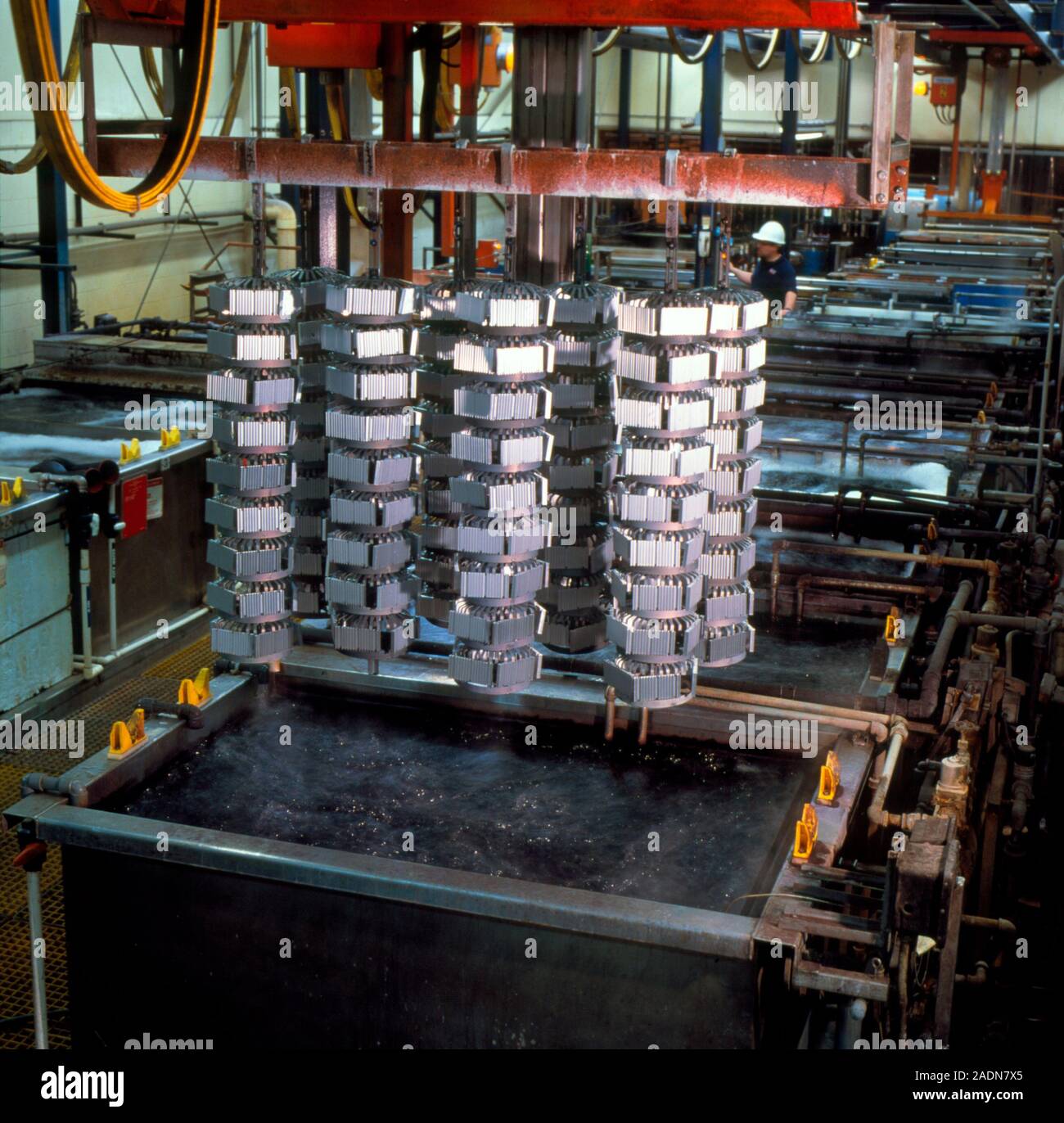 Electroplating. Rack of objects above an electro- plating tank ...