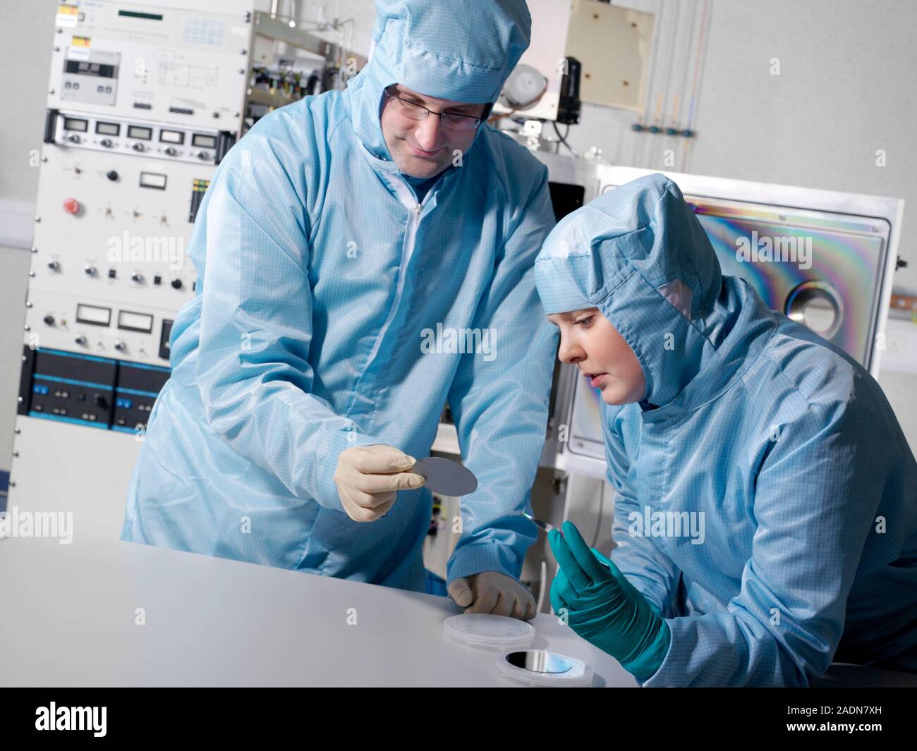 Cleanroom facility. Technicians at work in a cleanroom facility. A ...