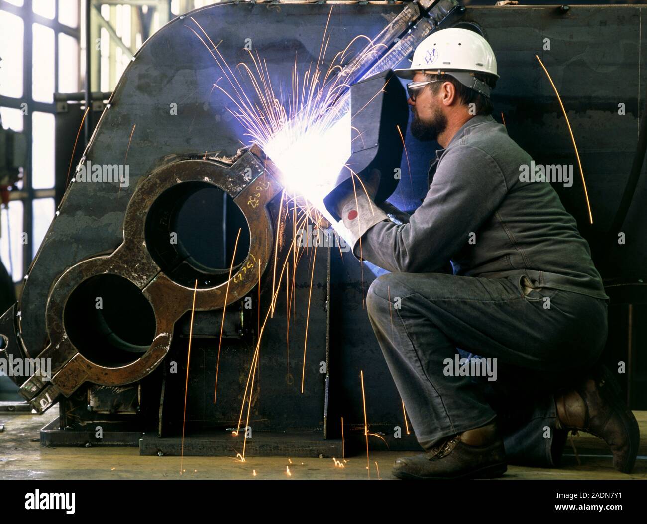 Welding. Man creating a shower of sparks as he welds a connecting seam ...