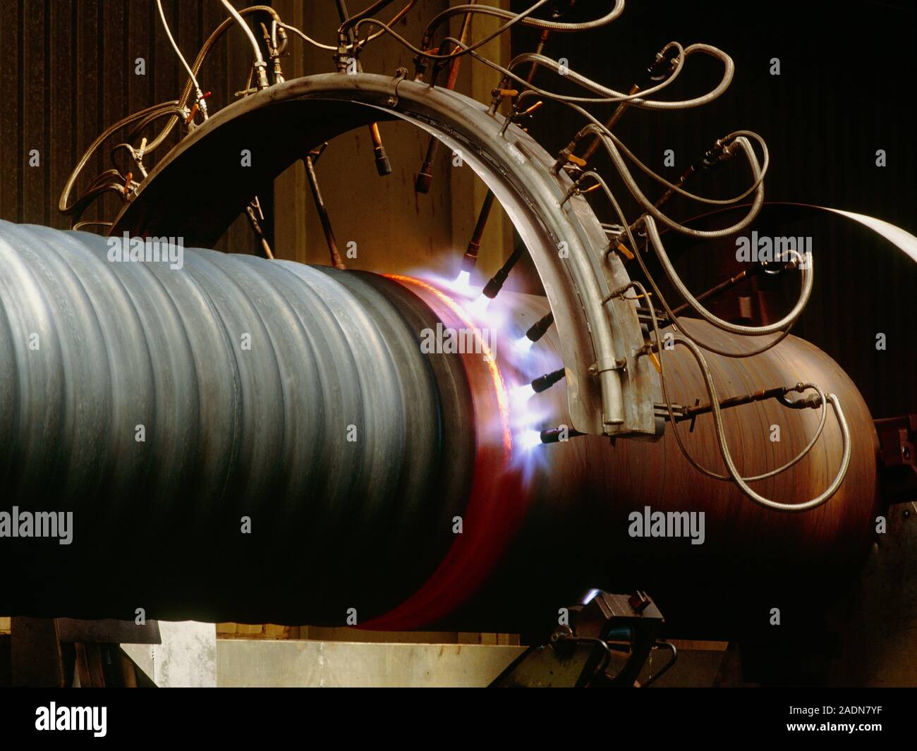 Welding machine bonding pipes together during construction of a boiler ...