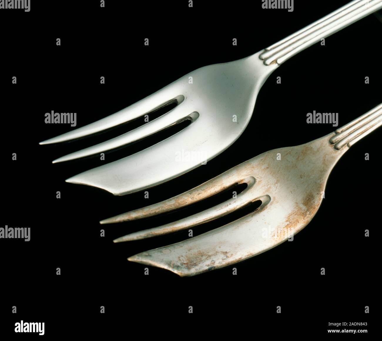 Tarnished silver. Tarnished (bottom) and untarnished (top) silver forks ...