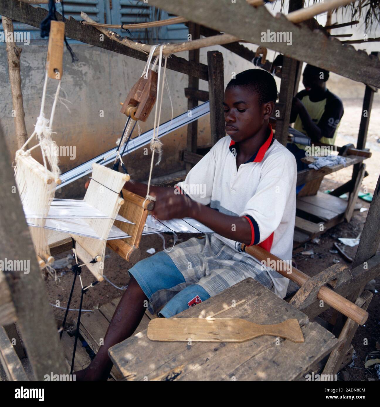 Kente cloth weaving. Young boy hand-weaving a traditional Asante ...