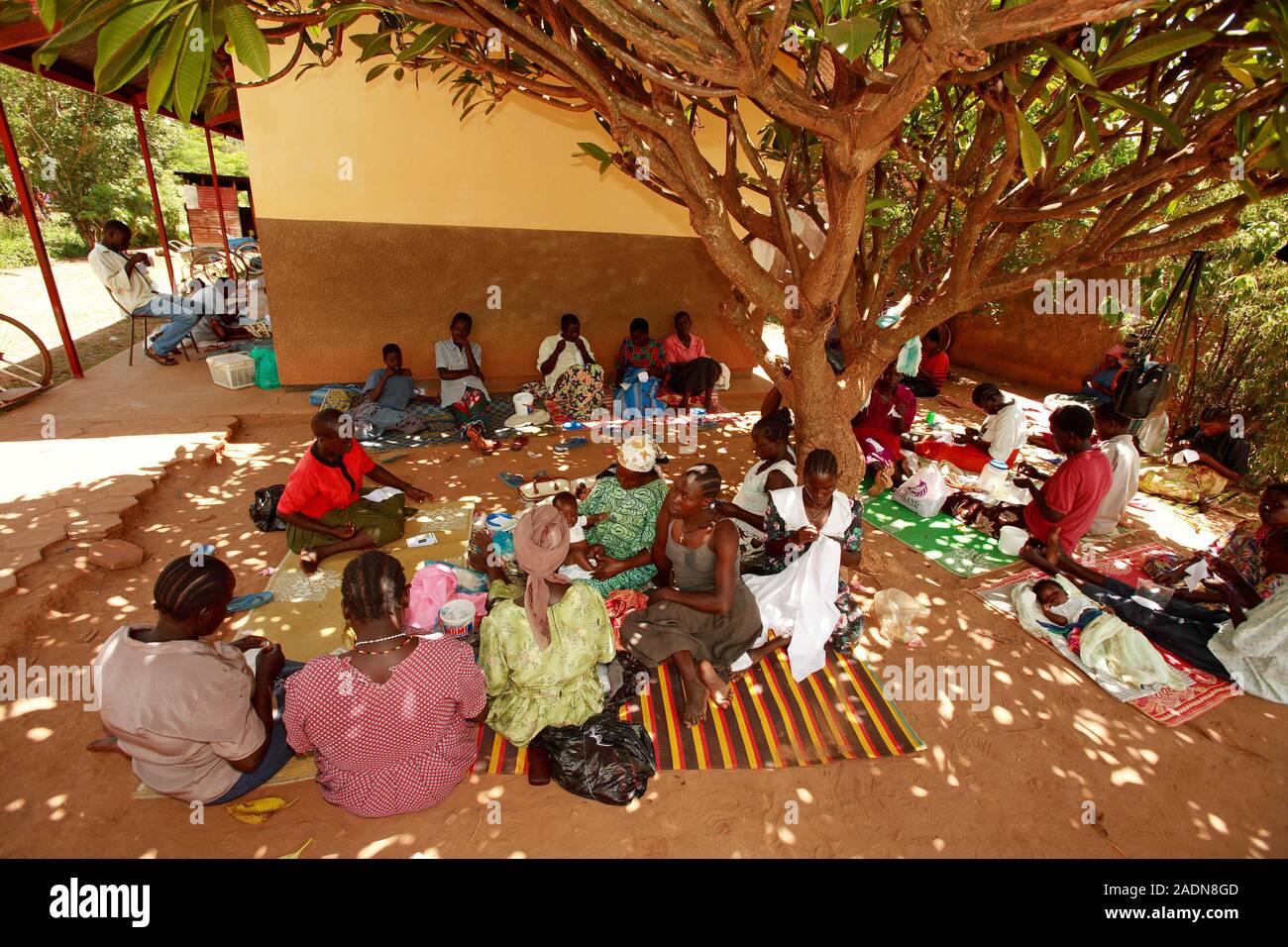 Village crafts. Villagers engaged in traditional crafts under a tree ...