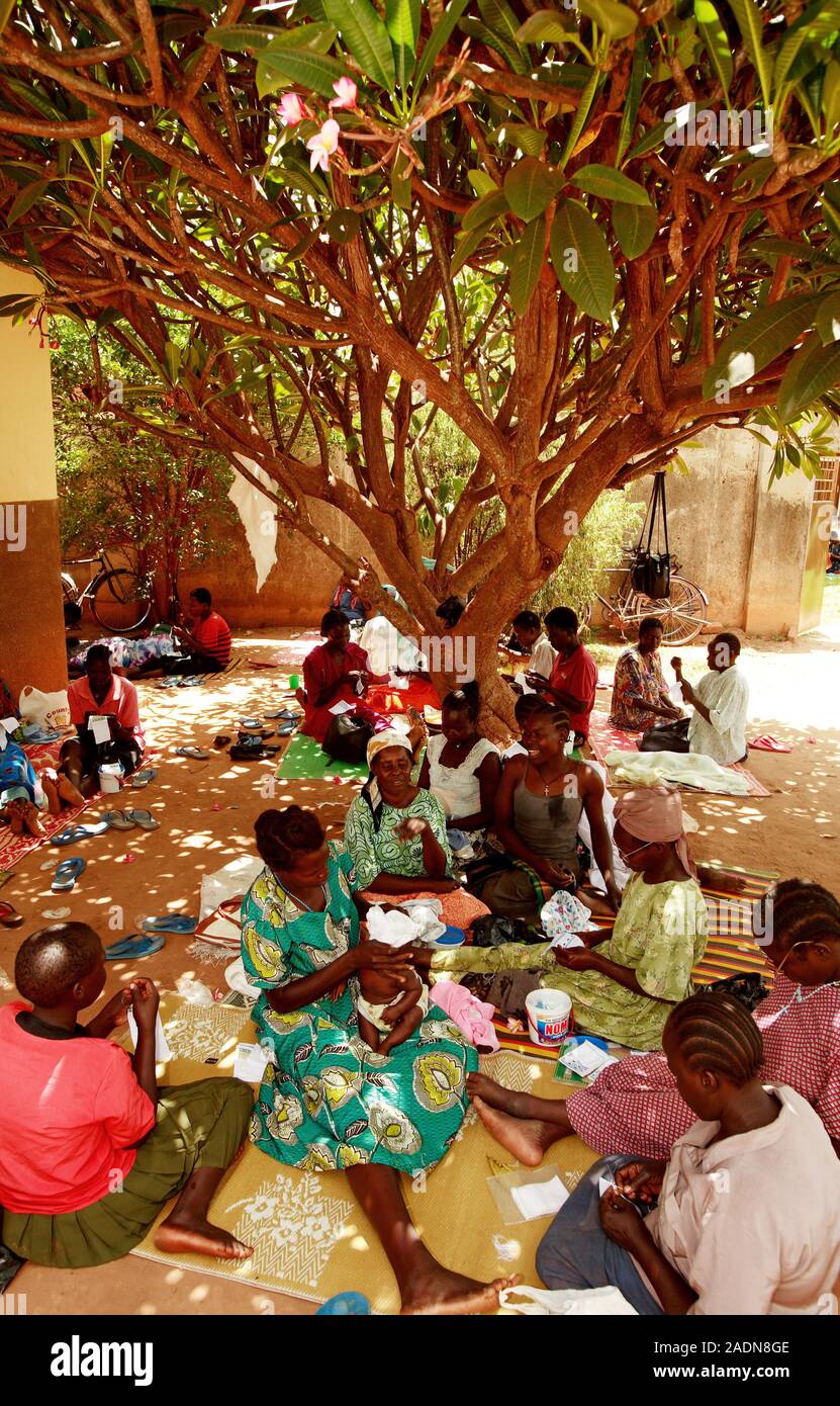 Village crafts. Villagers engaged in traditional crafts under a tree ...
