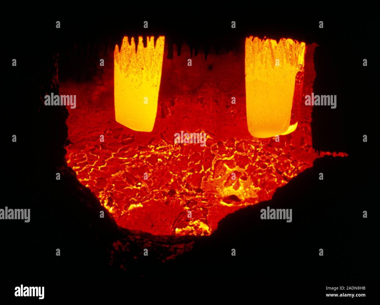 Two large graphite electrodes glow above the melt in a furnace after a ...