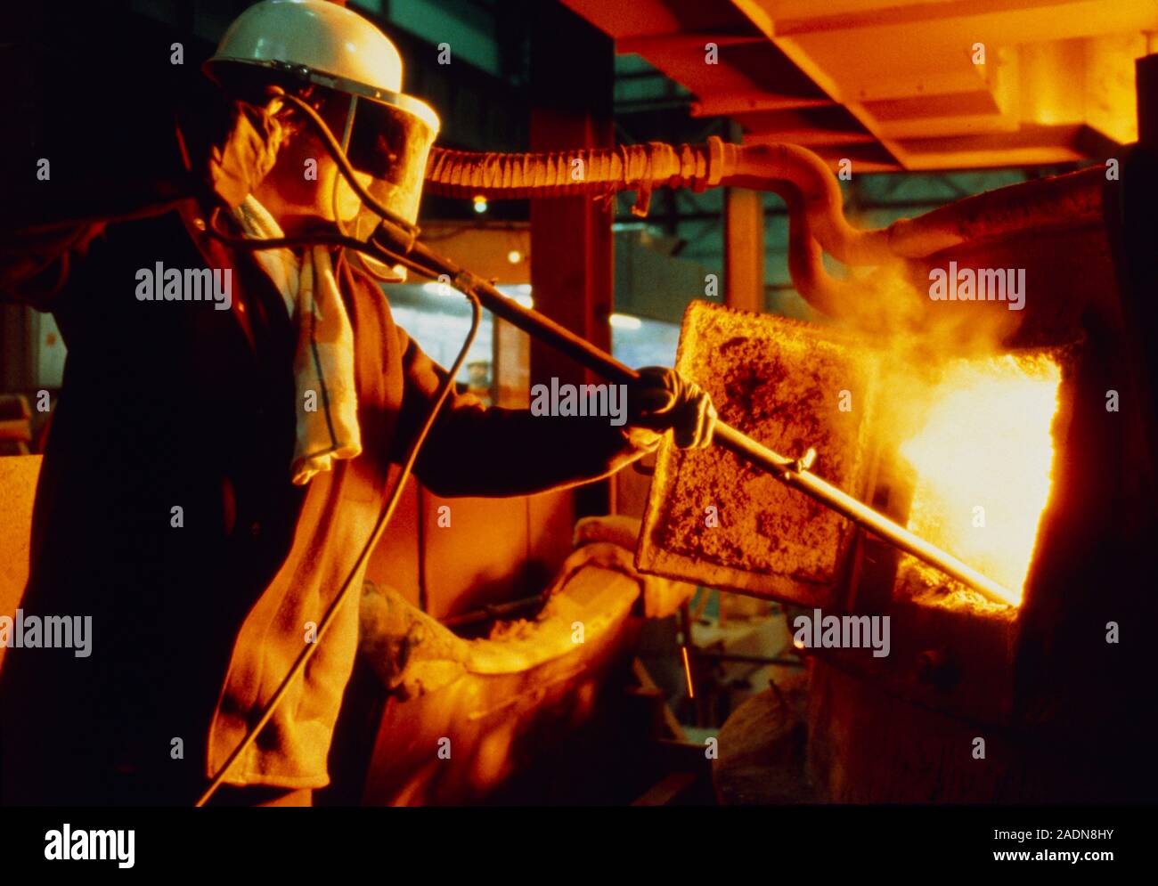 Steel production: a worker checking the contents of an electric arc ...