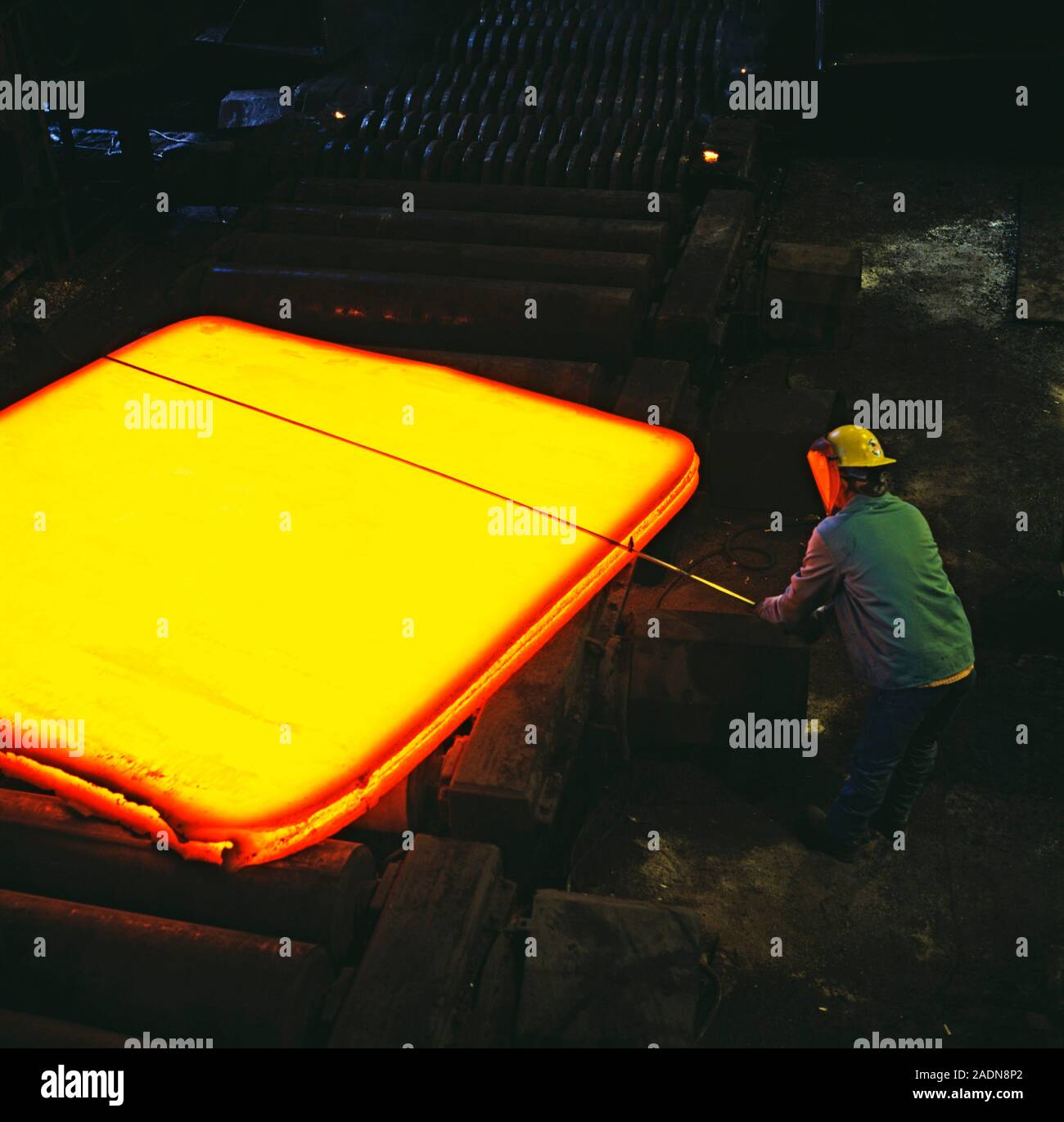 Steel. Steelworker with a slab of glowing steel. Photographed at ...