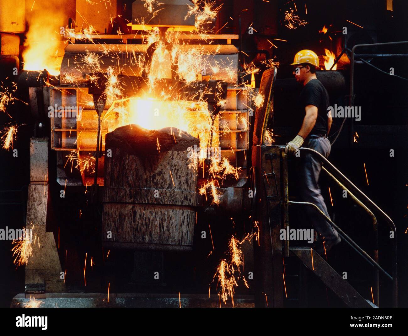 MODEL RELEASED. Steel production. Worker overseeing the pouring of ...