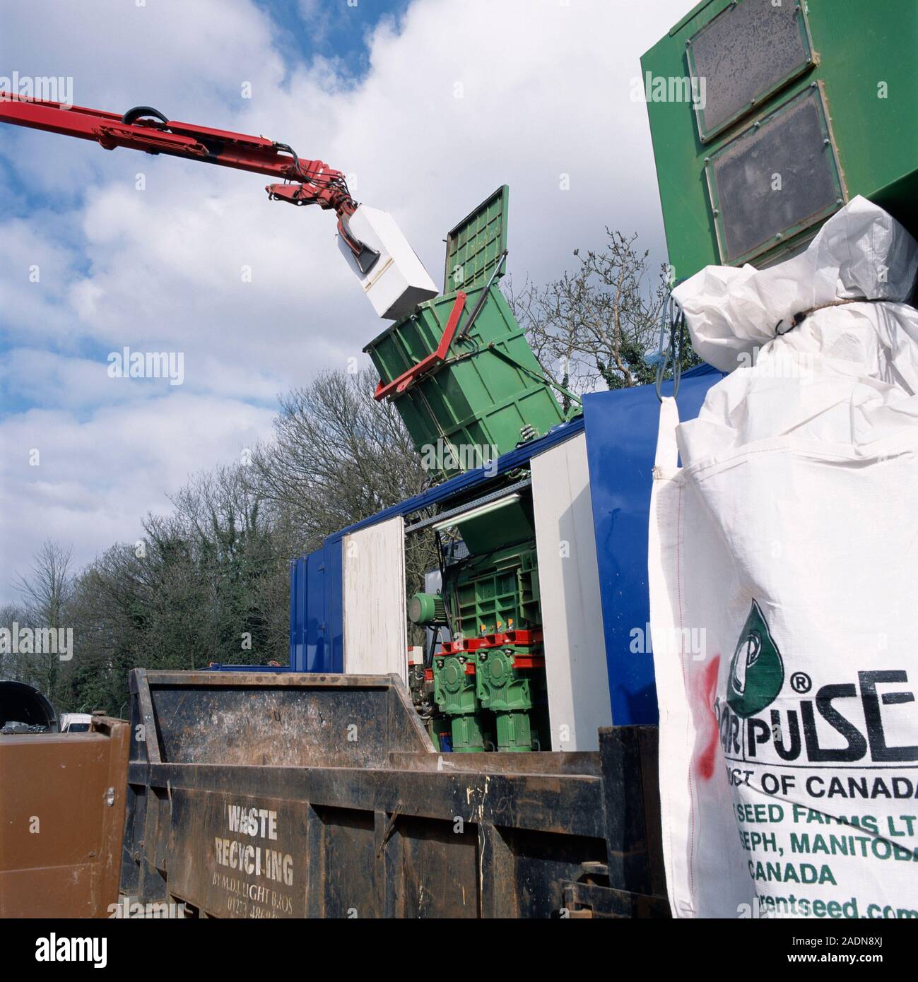 Refrigerator recycling. Refrigerator being lifted into a crusher, which ...