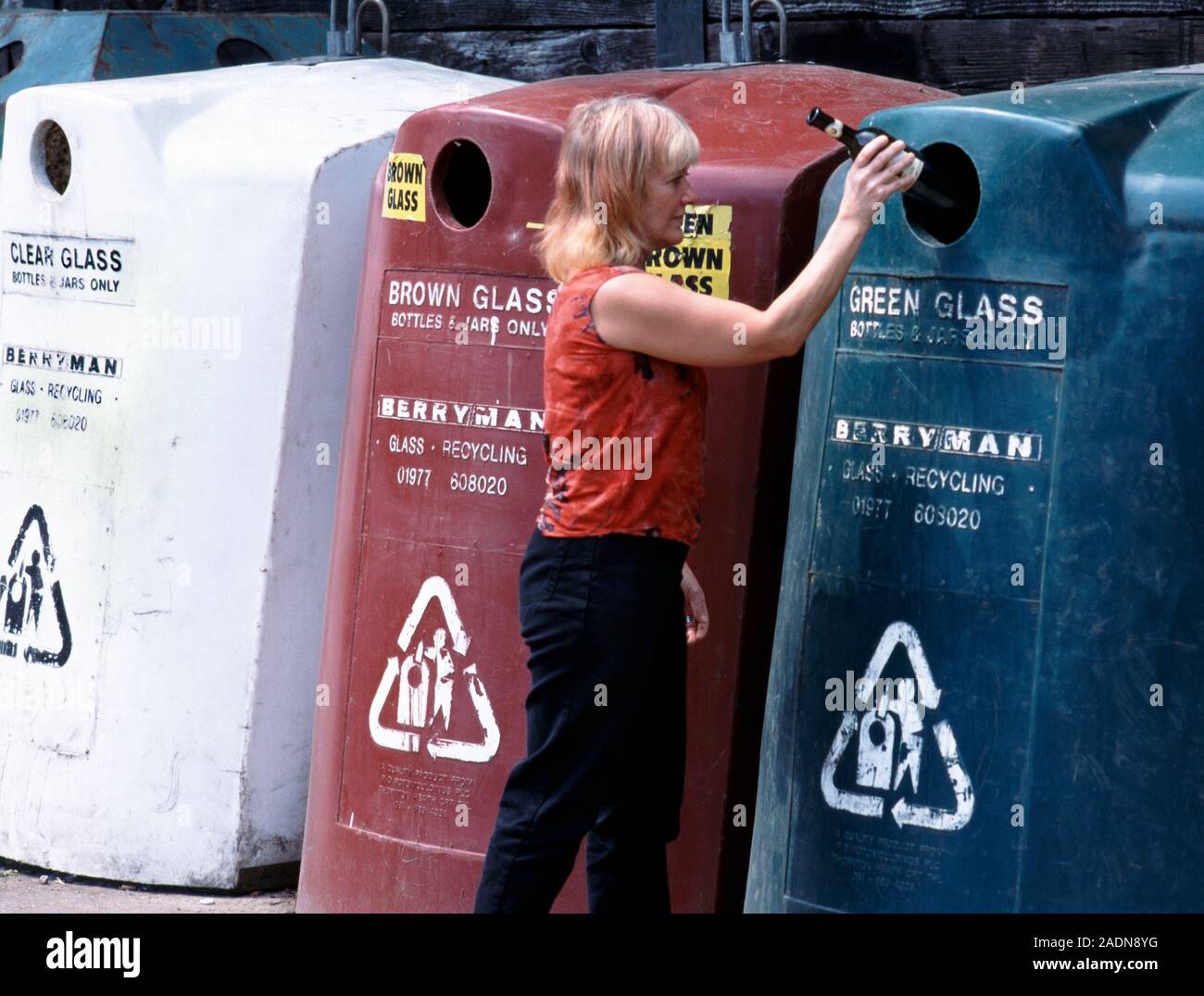 Recycling glass. Woman putting a green glass bottle into the correct ...