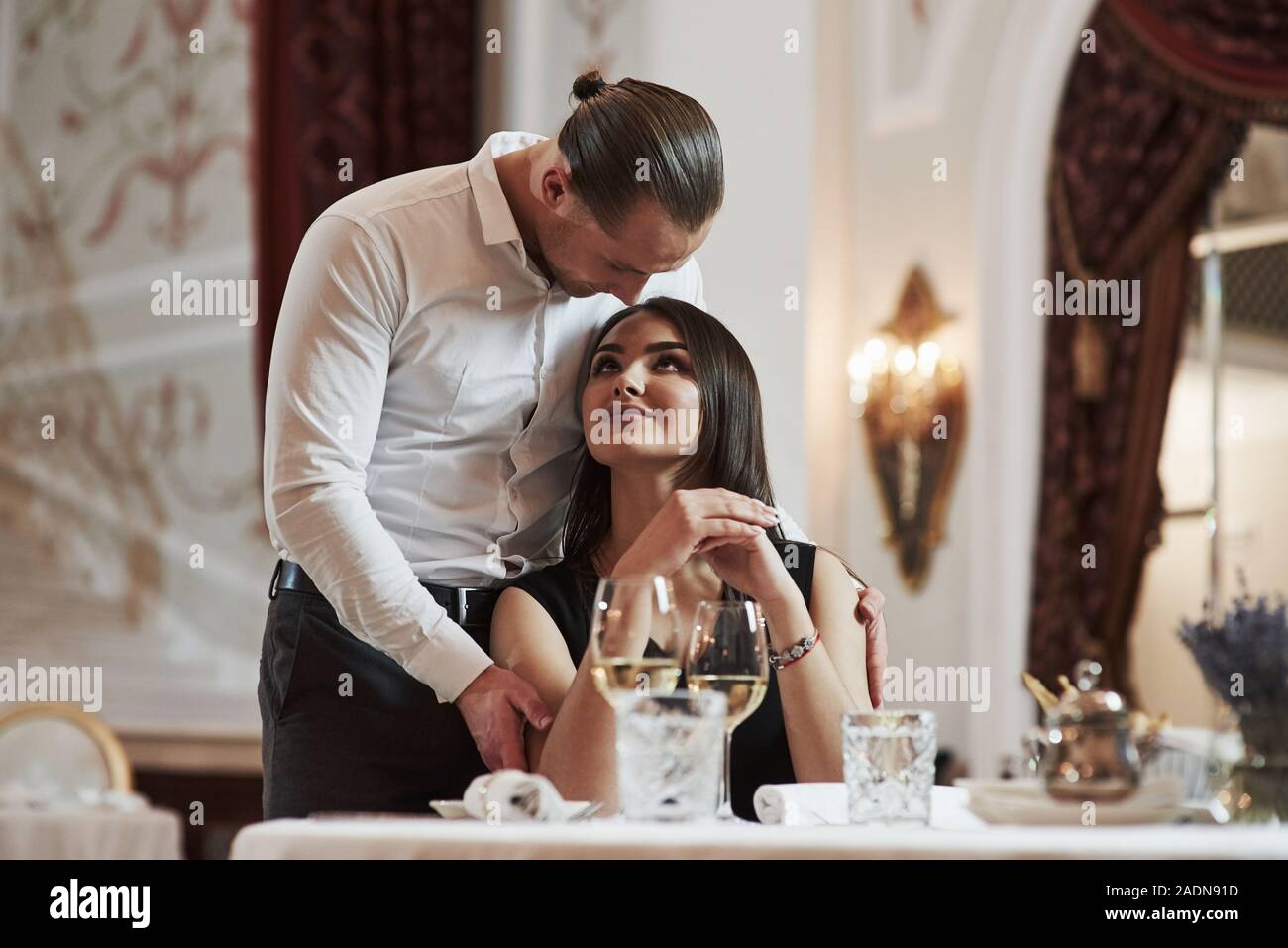 Stands on the back of girlfriend. Beautiful couple have romantic dinner ...