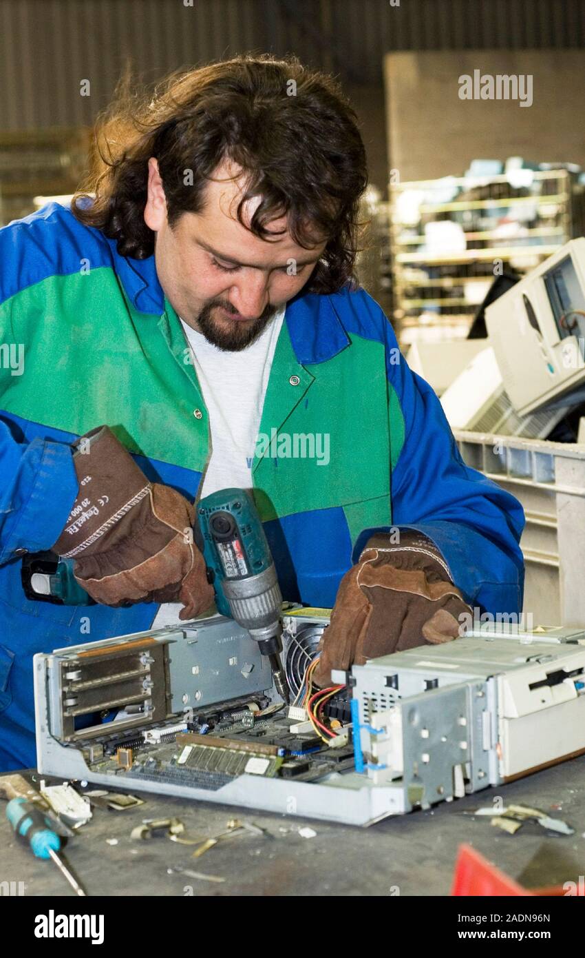 Recycling computer equipment. Worker using an electric screwdriver to ...