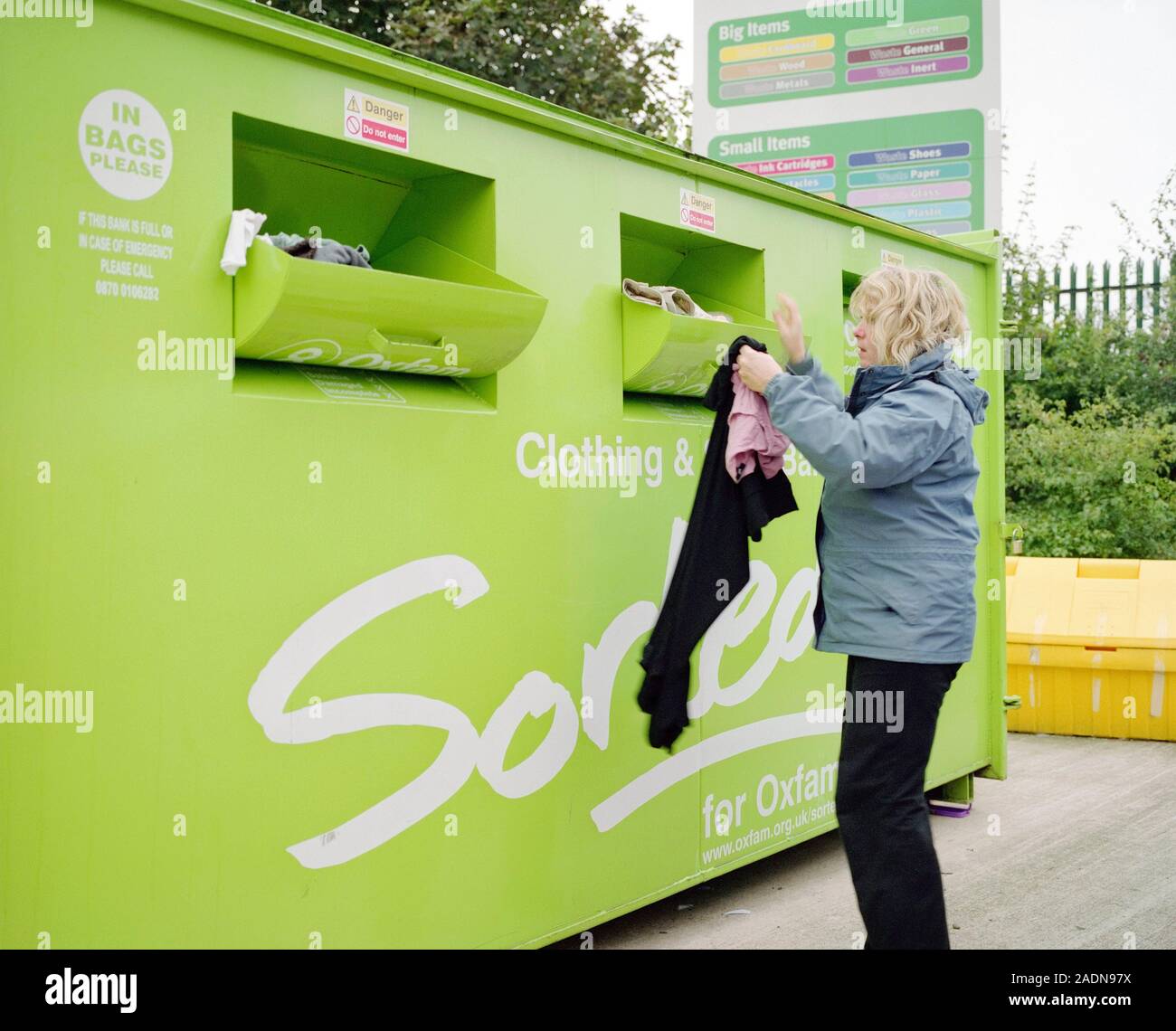 MODEL RELEASED. Clothing bank. Woman placing unwanted clothes in a ...