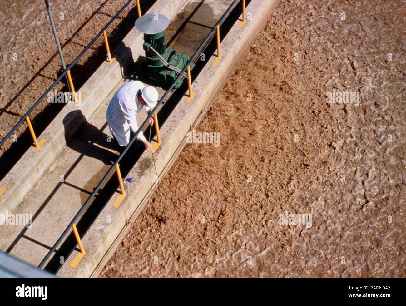 Water treatment plant. A technician taking a water sample from a bridge ...