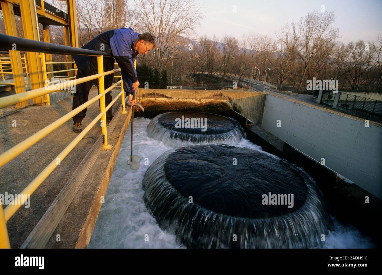 Water industry. Worker sampling water near the intake pipes for a ...