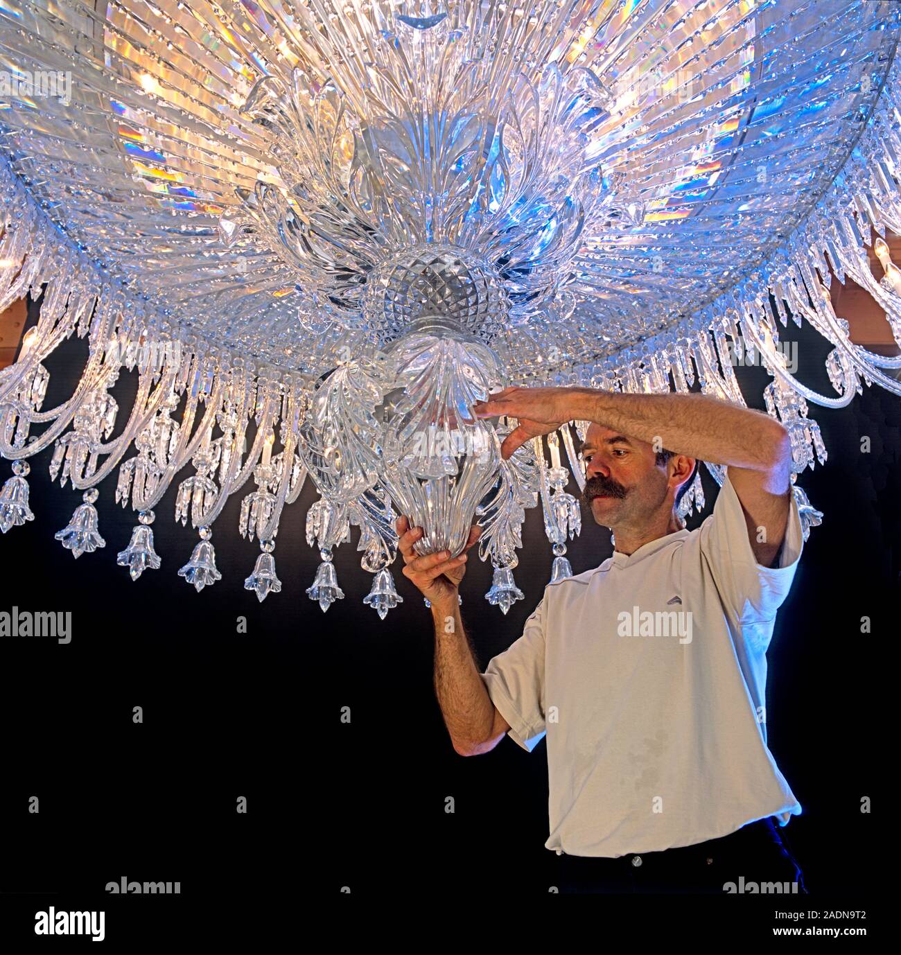 Crystal glassware chandelier. Worker assembling a crystal glass ...
