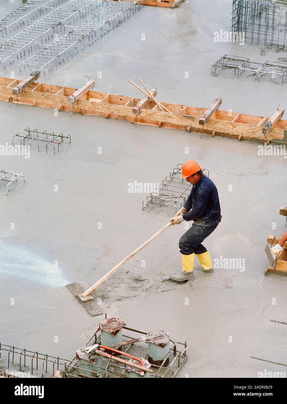 Building site. Construction worker smoothing out freshly laid concrete ...