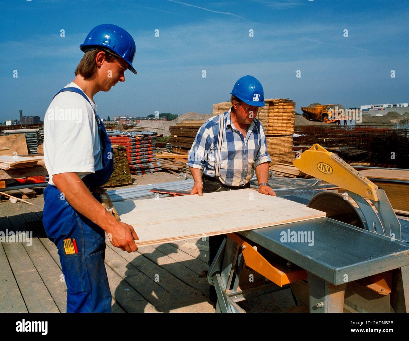 Building site. Construction workers using a powered saw to cut a piece ...