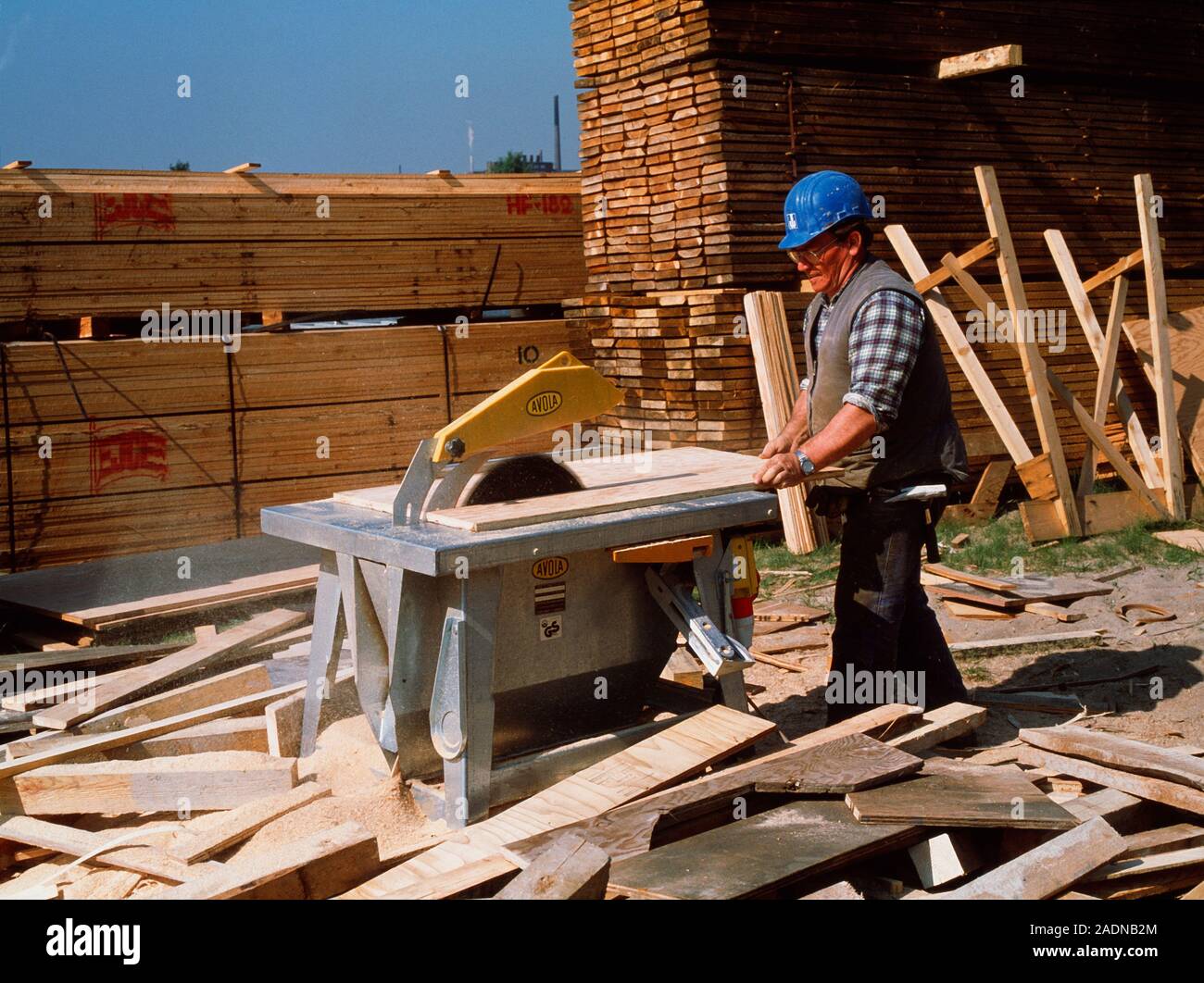 Building site. Construction worker using a powered saw to cut wood ...