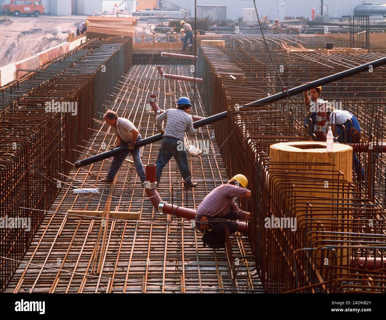 Building site. Construction workers handling pipes and working on a ...