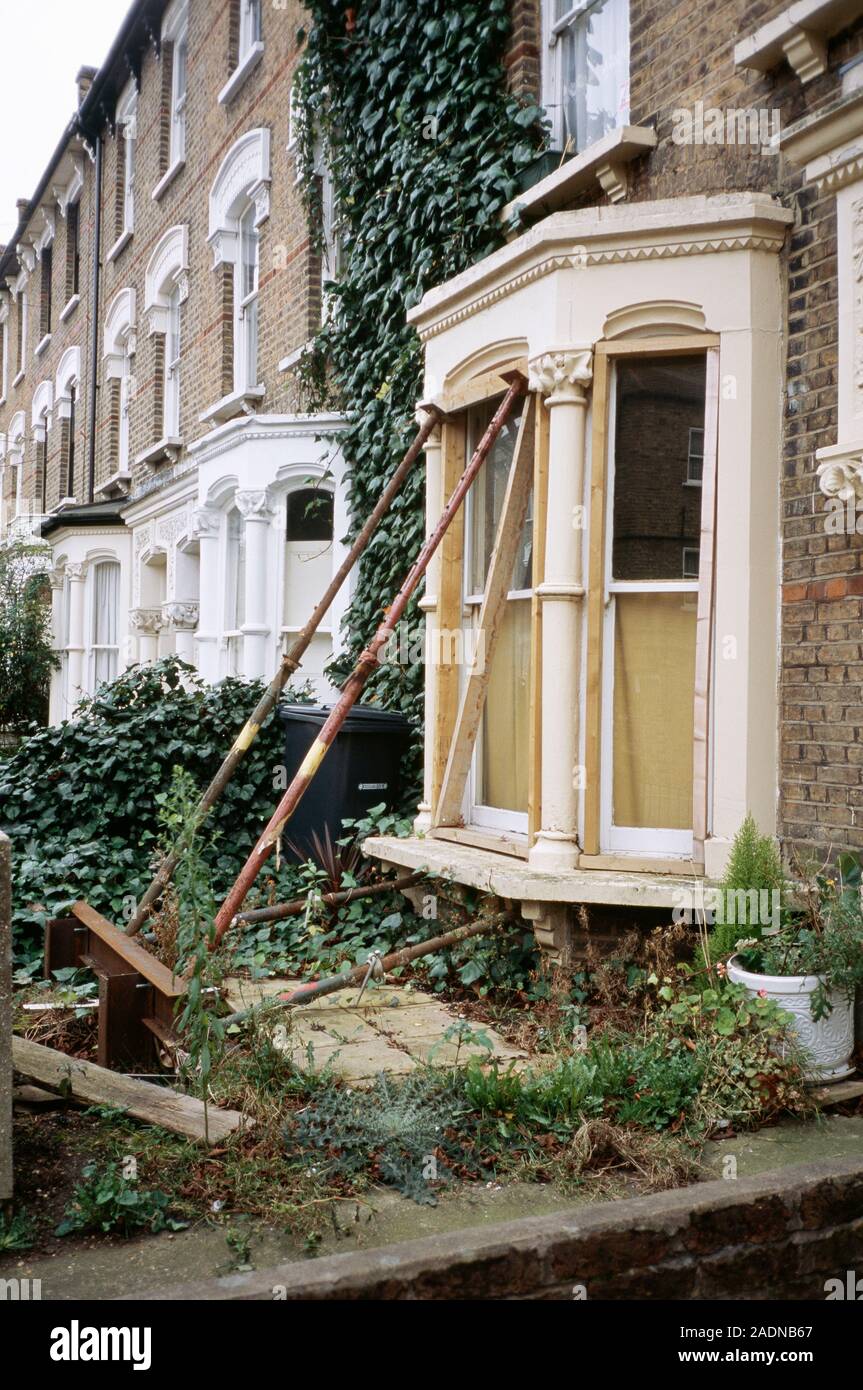 Subsiding house being supported against collapse by metal struts ...