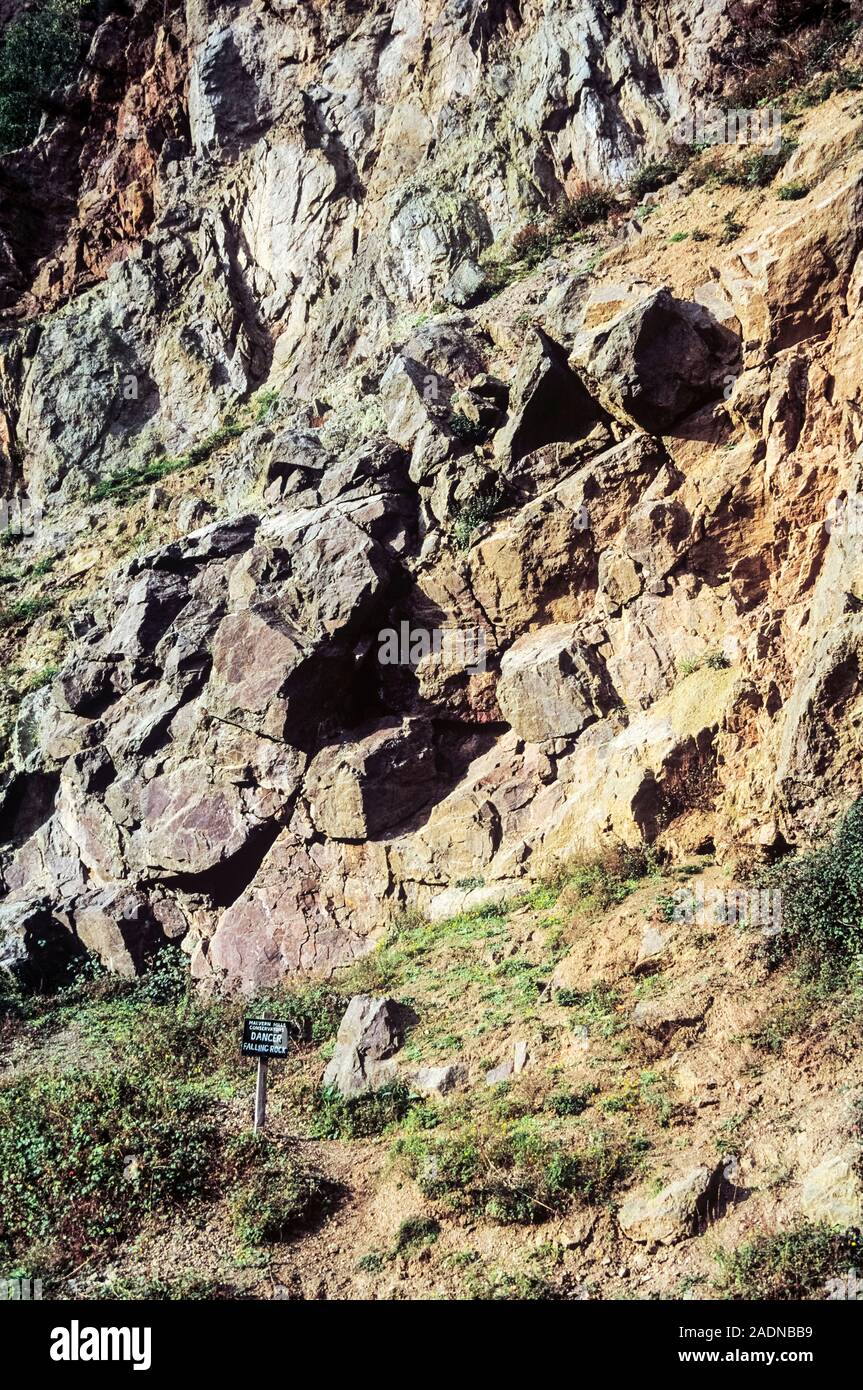 Quarry sign. Sign warning of possible rock falls at the base of a cliff ...