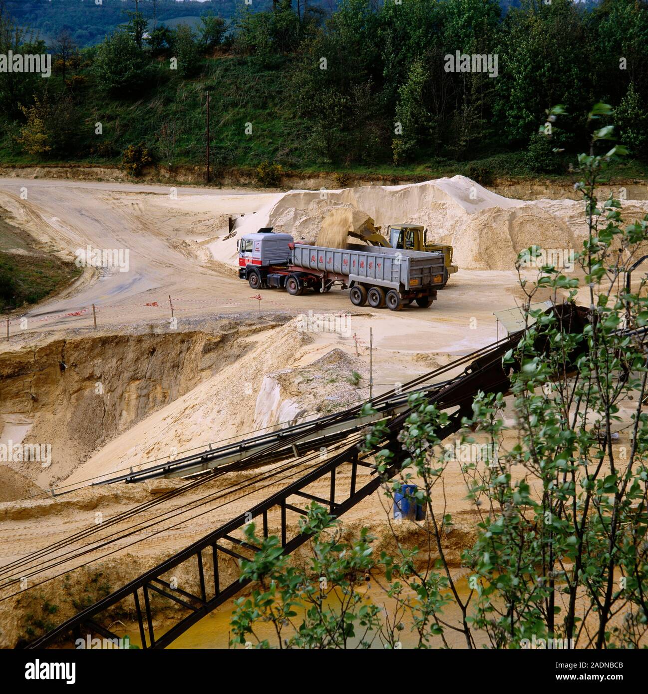 Sand quarry. Digger loading a truck with sand at a sand quarry. Sand is ...