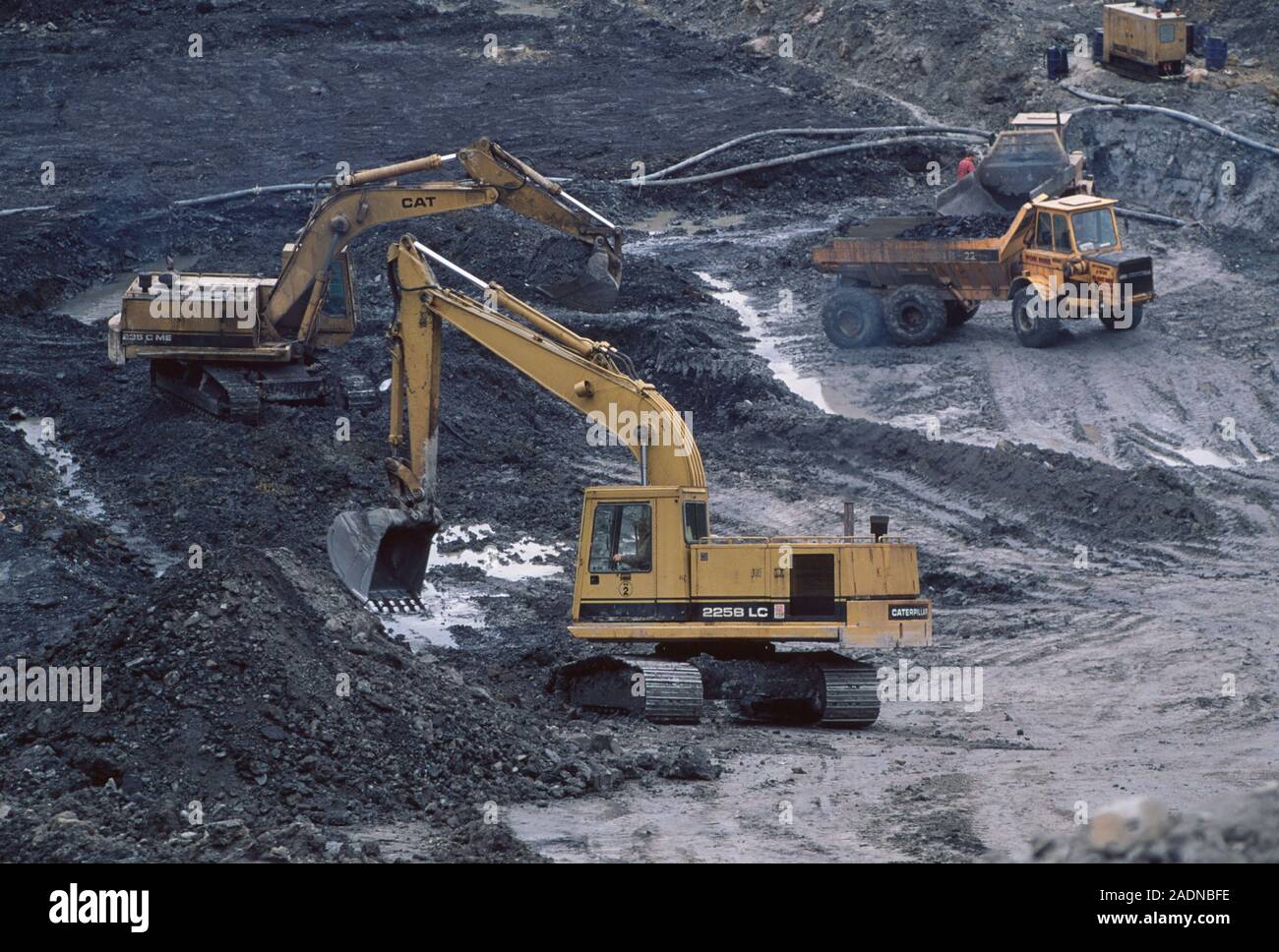 Open-cast coal mining. Diggers and trucks transporting coal debris at ...