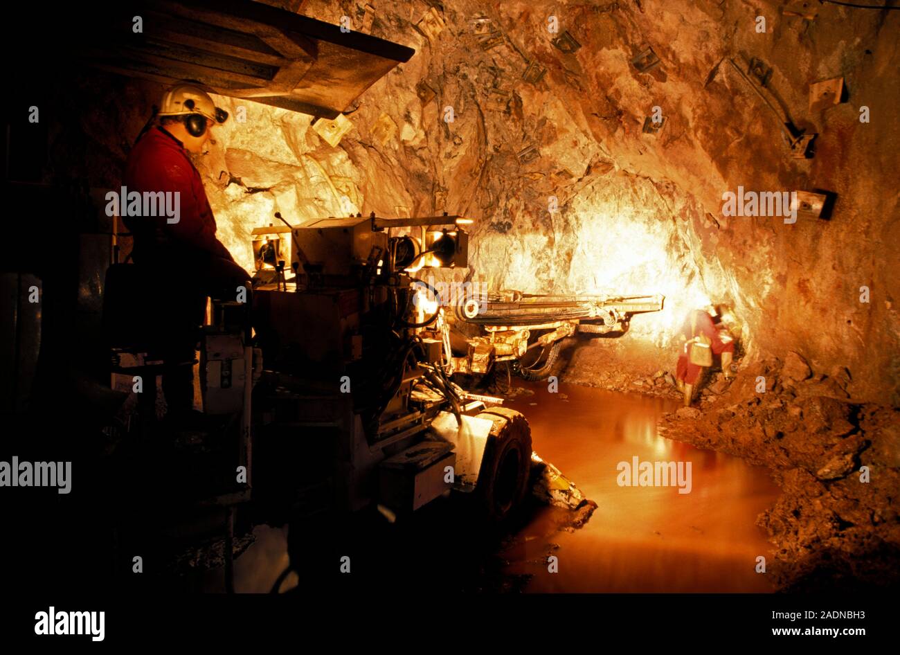 Uranium mining. Miner operating an excavation machine in a uranium mine ...