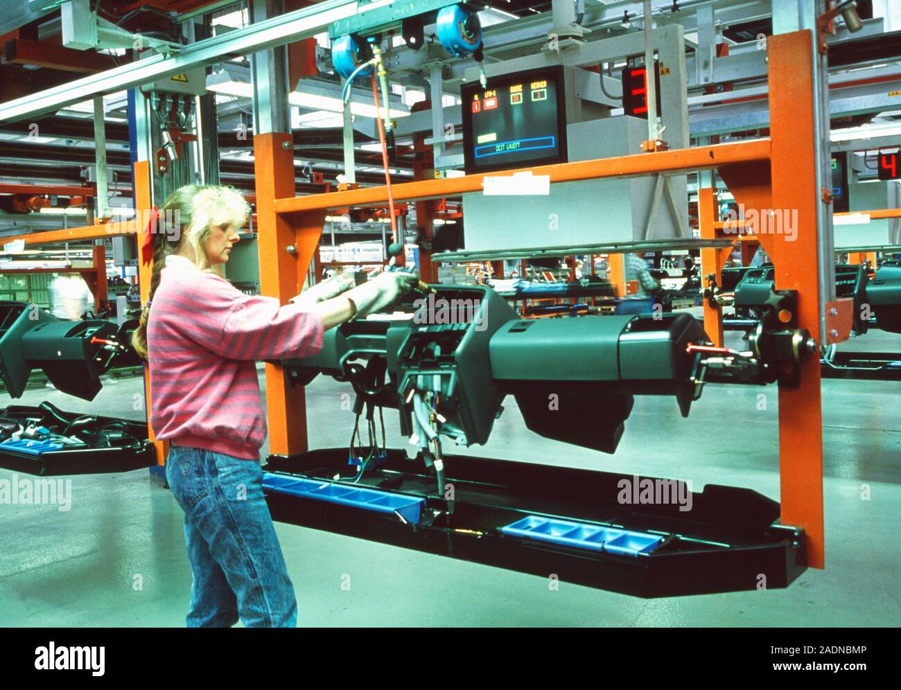 Assembly line worker building a car dashboard. Car parts are produced ...