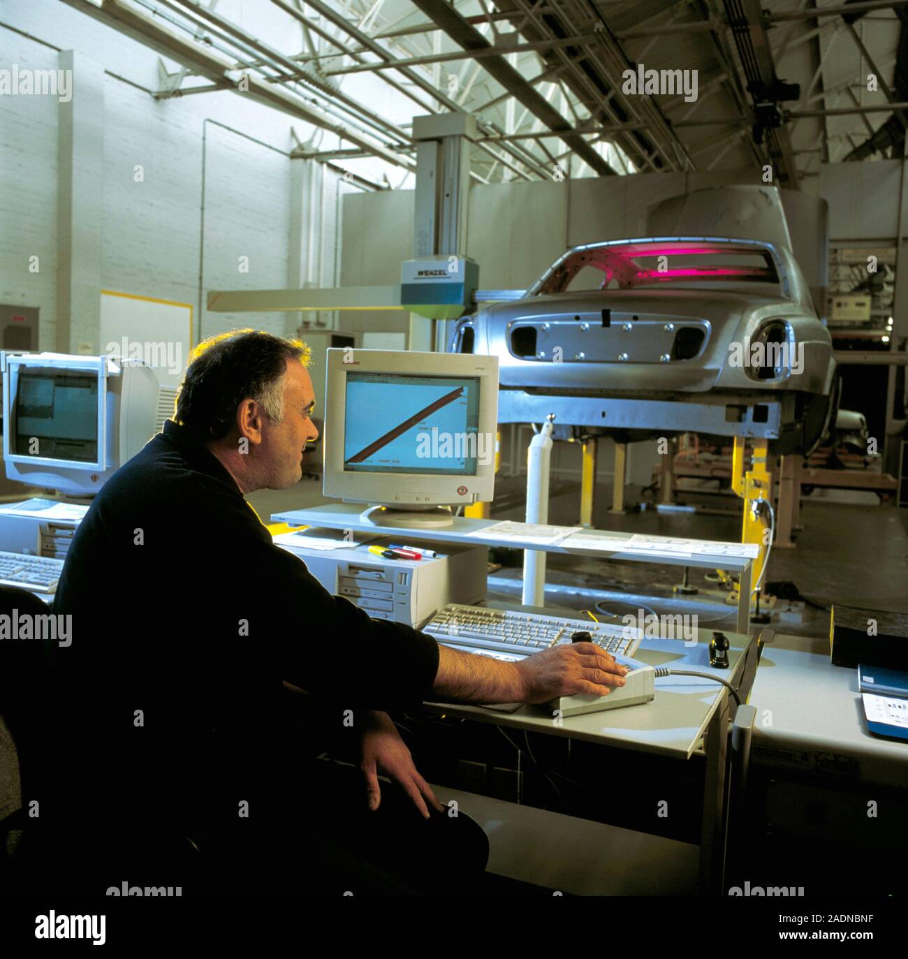 Car body measurement. Engineer using a computerised measurement system ...