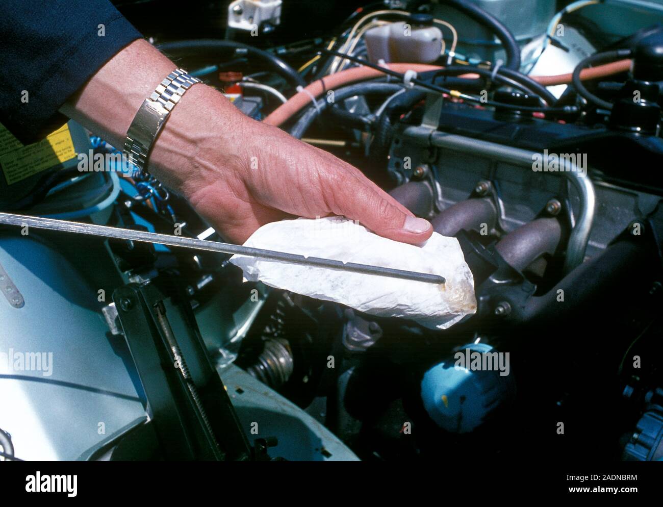 Engine oil check. Dipstick being used to measure the amount of oil ...