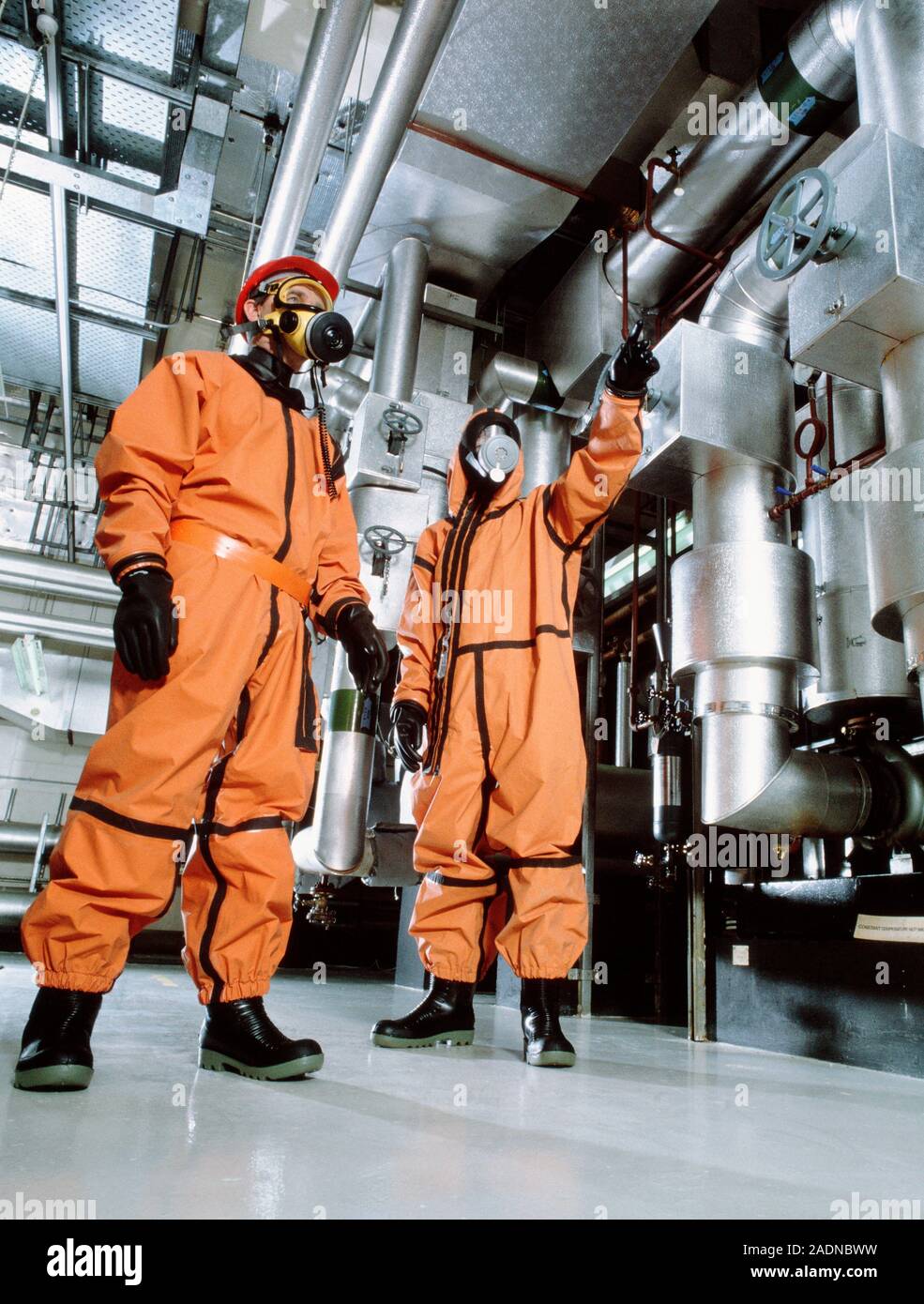 Chemical suits. Two workers in protective clothing in a chemical plant ...