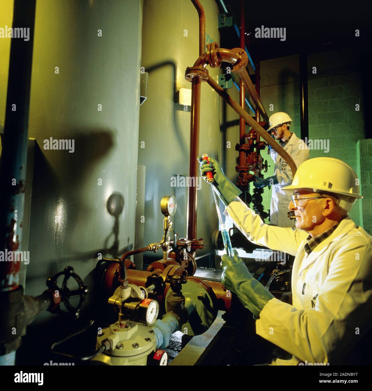 Chemical factory. Industrial chemist taking a sample to monitor ...