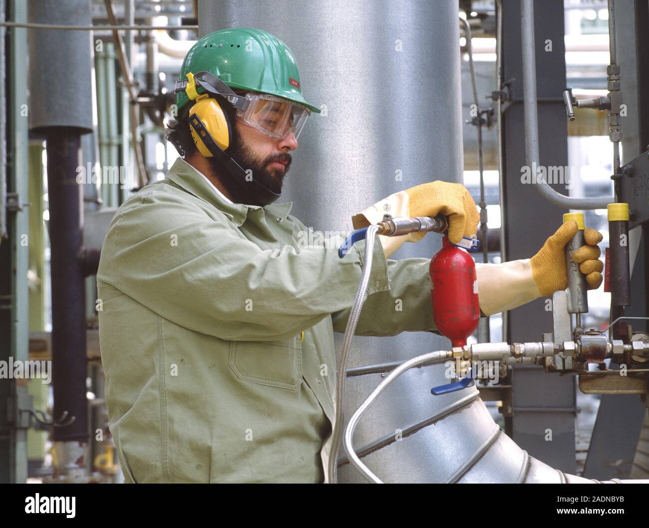 Gas sampling. Man adjusting valves on an industrial pipeline to obtain ...