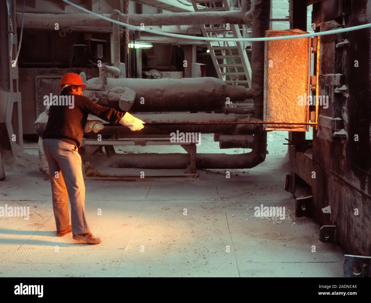 Lime kiln. The kiln operator is removing a sample of burned lime from ...