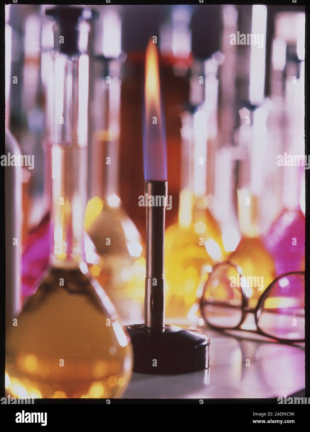 Bunsen burner. Lit bunsen burner with volumetric flasks, and safety ... Bunsen burner. Lit bunsen burner with volumetric flasks, and safety ...