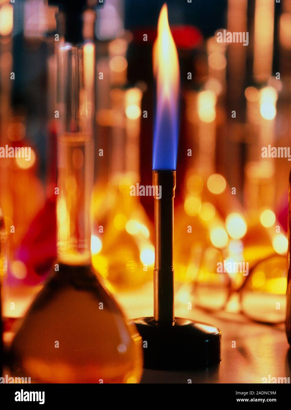 Bunsen burner. Lit bunsen burner with volumetric flasks, and safety ... Bunsen burner. Lit bunsen burner with volumetric flasks, and safety ...