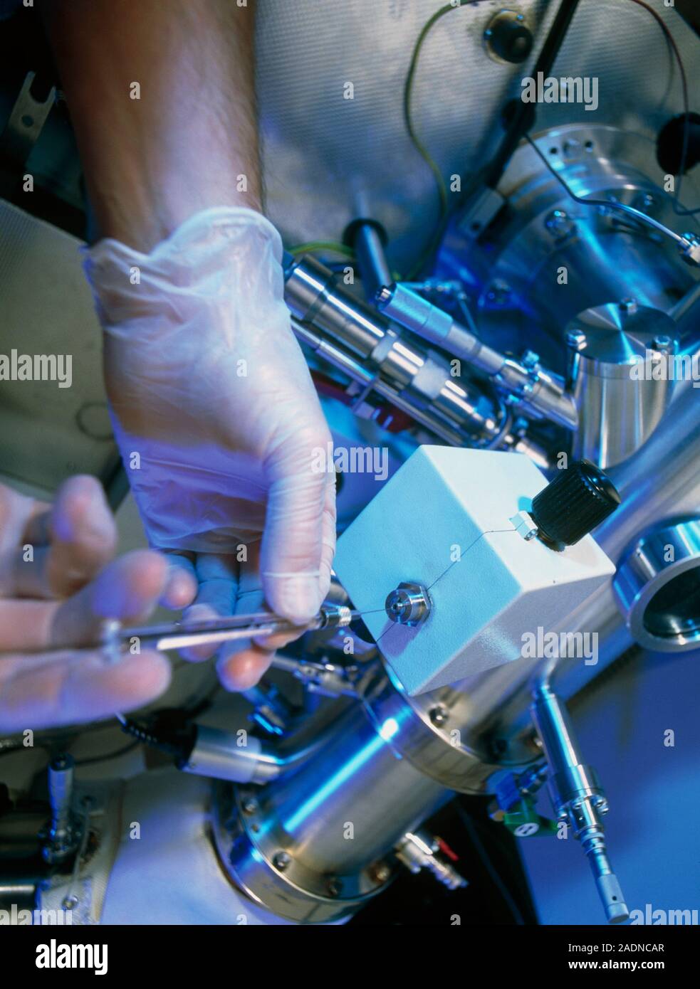 Mass spectrometry. Technician's gloved hands injecting a sample into a ...