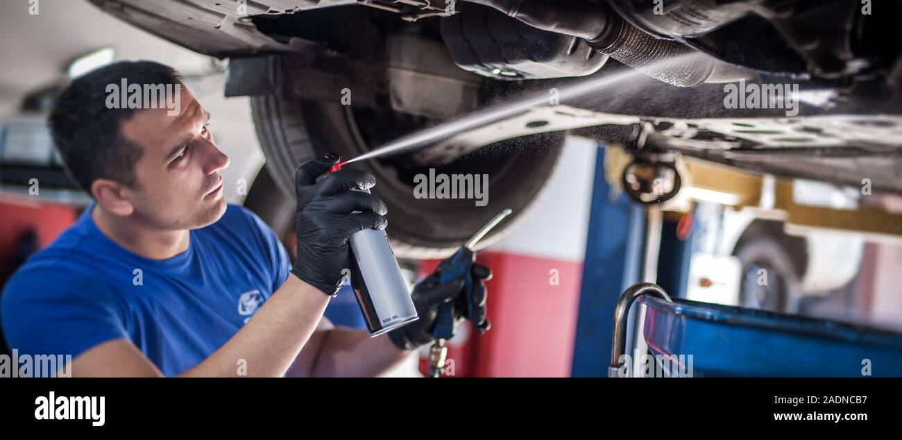 Car master mechanic repairer lubricates the screws with a machine parts ...