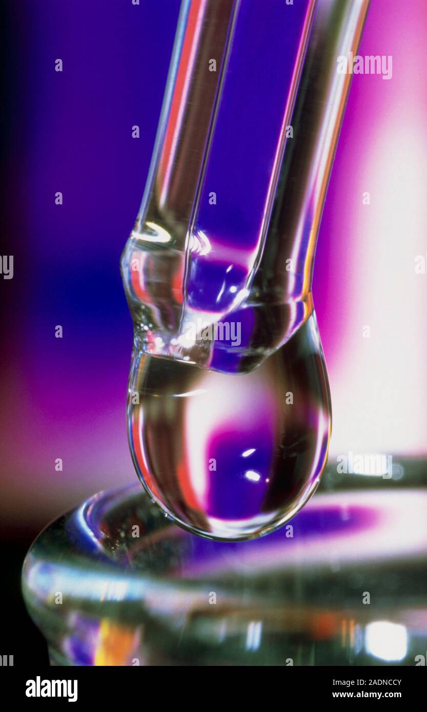 Pipette. Close up of a droplet of clear liquid hanging from a pipette ...