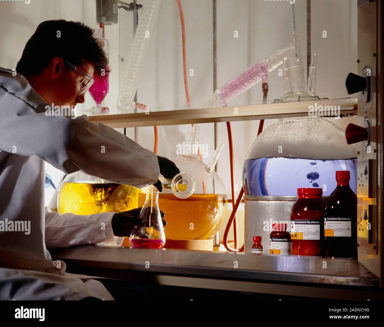 Chemist. Chemist pouring liquid from a measuring cylinder into a ...