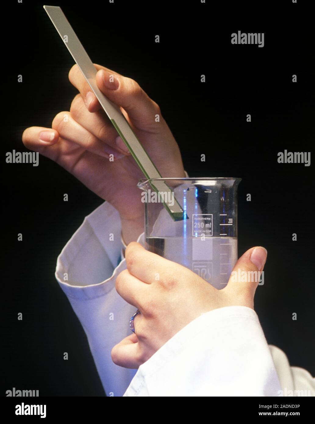 Laboratory test. Female scientist testing the pH of a clear liquid in a ...