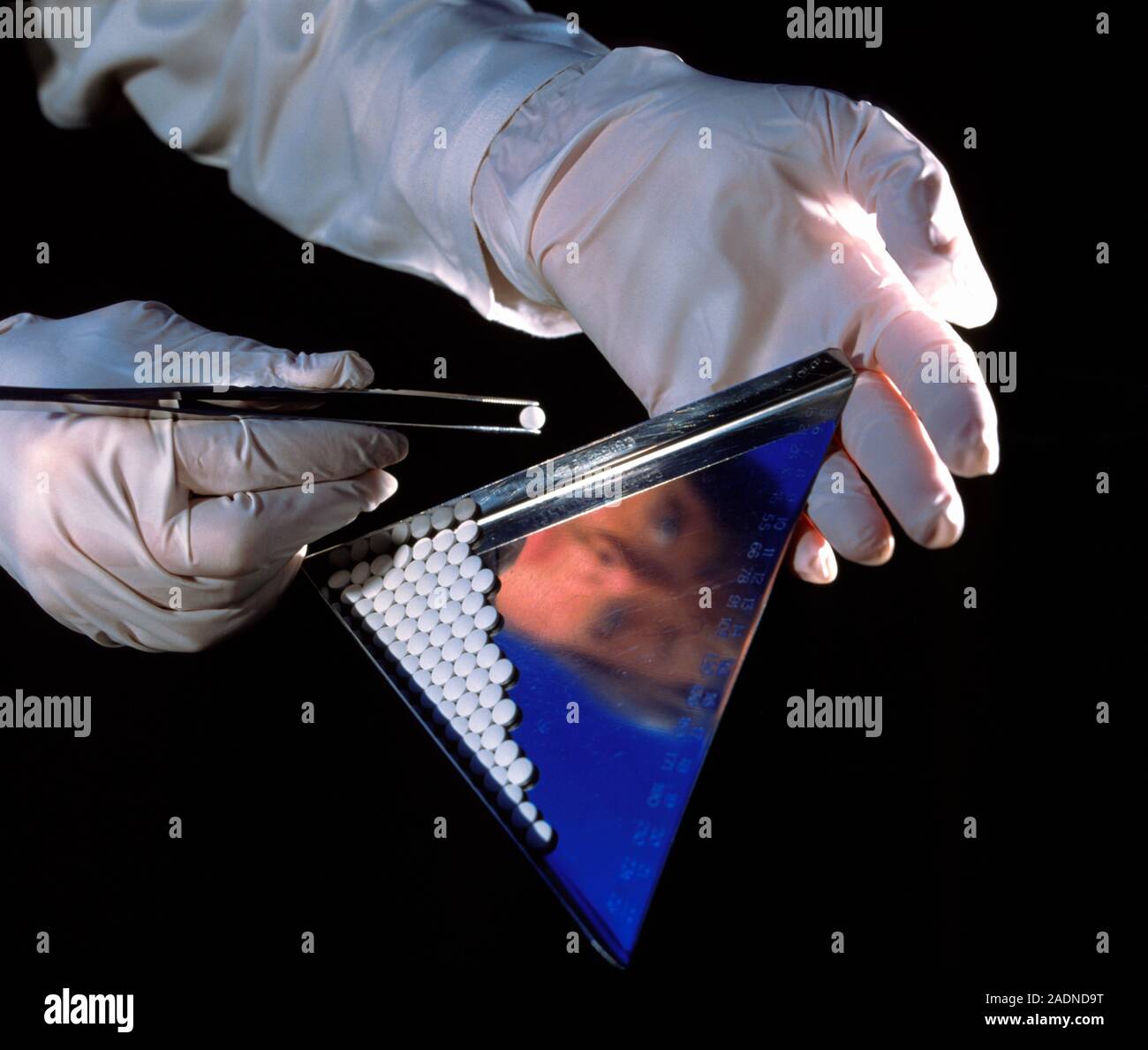 Pill inspection. Female technician visually inspecting a drug tablet or ...